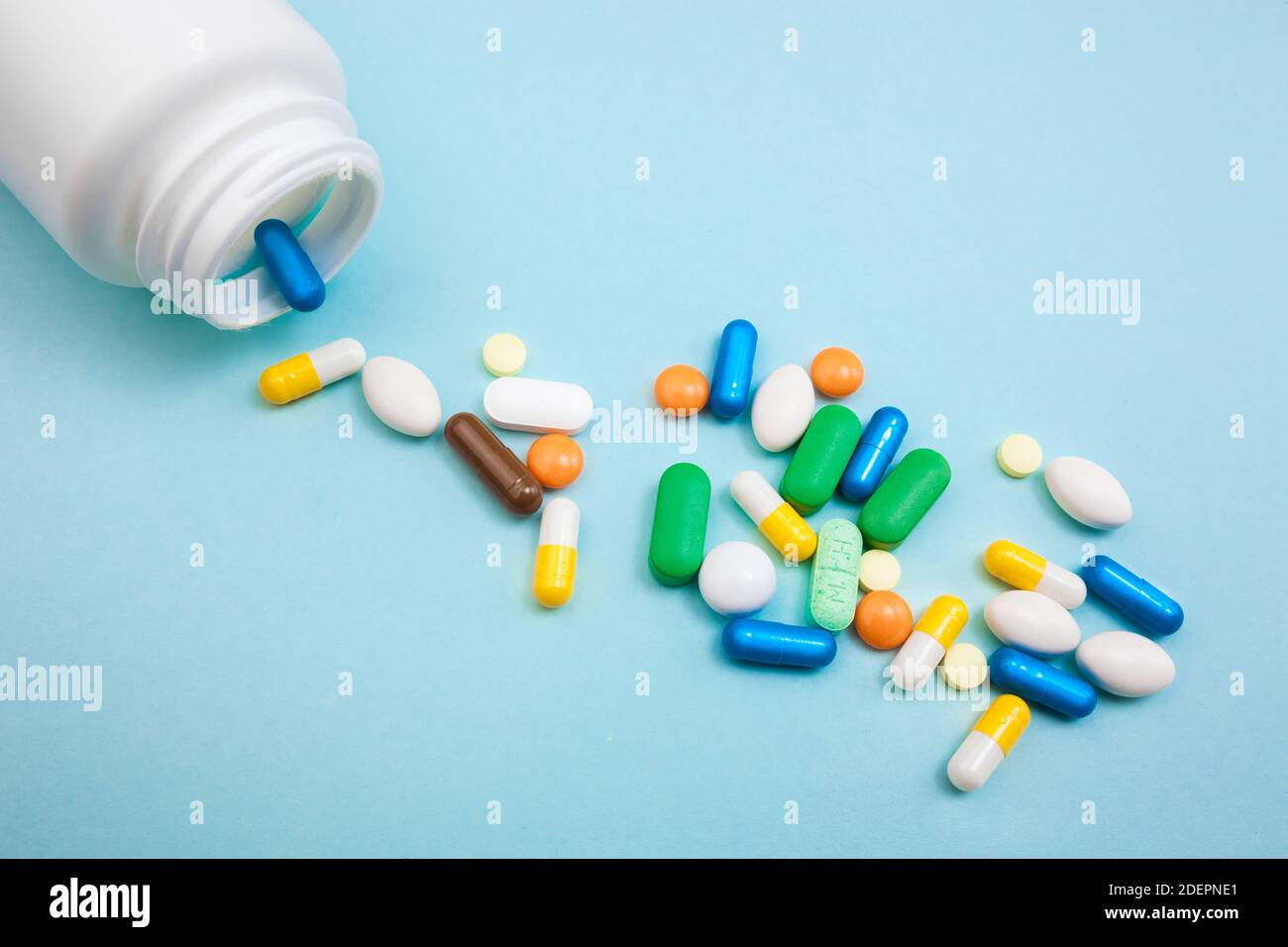 Multi-colored tablets and capsules, white bottle for tablets ...