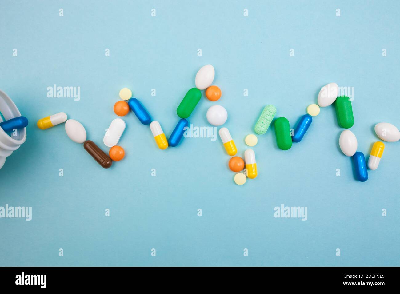 Multi-colored tablets and capsules in pulsation heartbeat white bottle ...