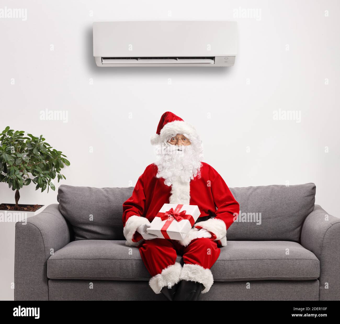Santa claus sitting on a sofa with a present under an air conditioner ...