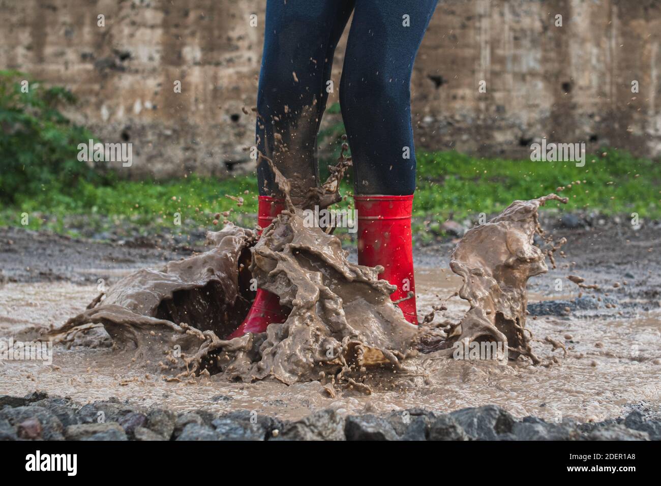 Legs of a girl jumping in a mud puddle, wearing red wellies, splashing mud Stock Photo - Alamy