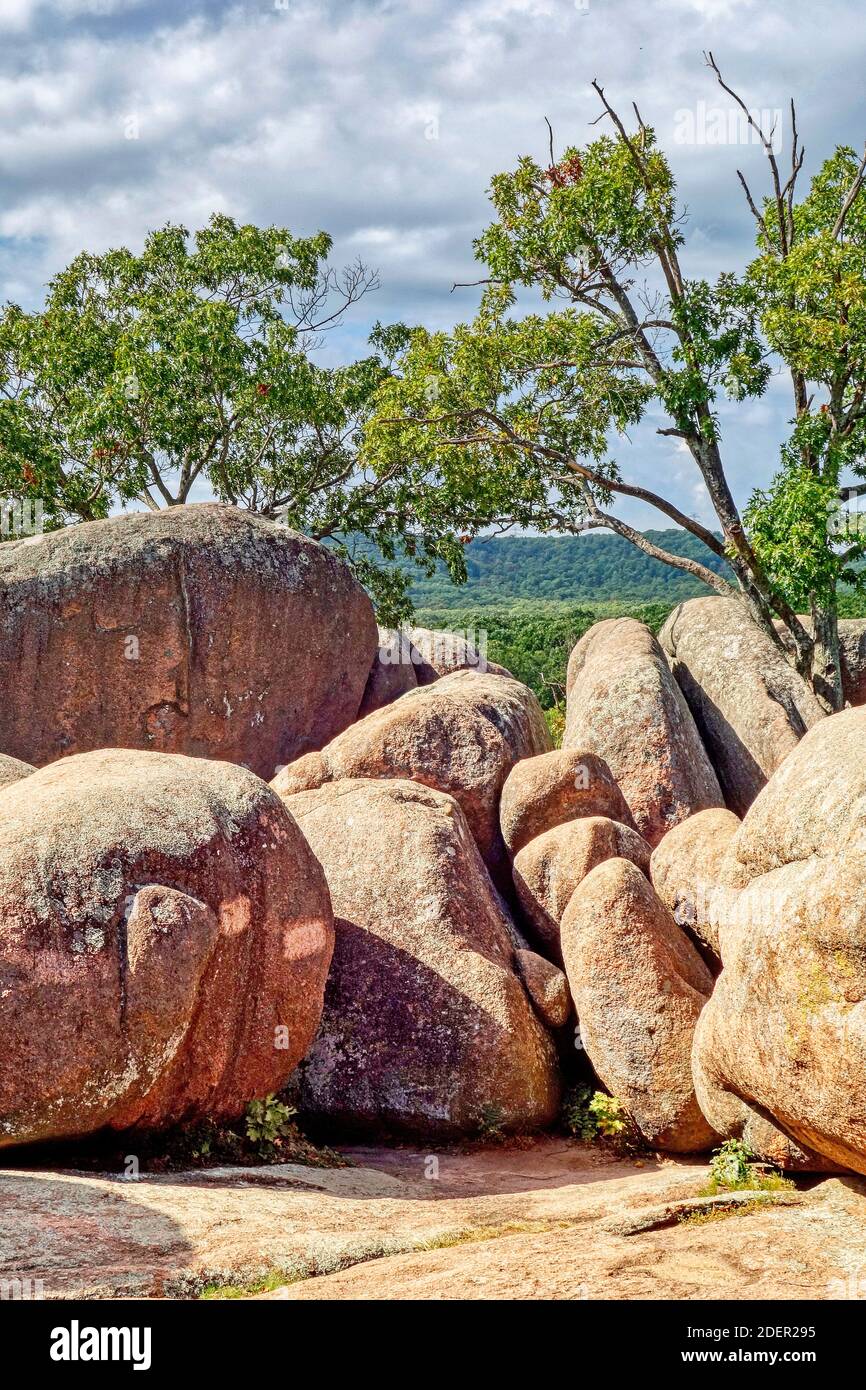 A vertical shot of rocks surrounded by greenery and hills under a ...