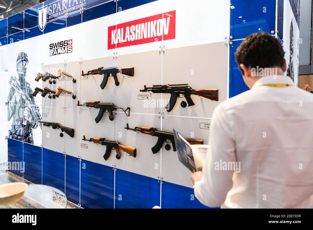 A visitor reads a brochure on a booth exhibiting Swiss Arms pistols and ...