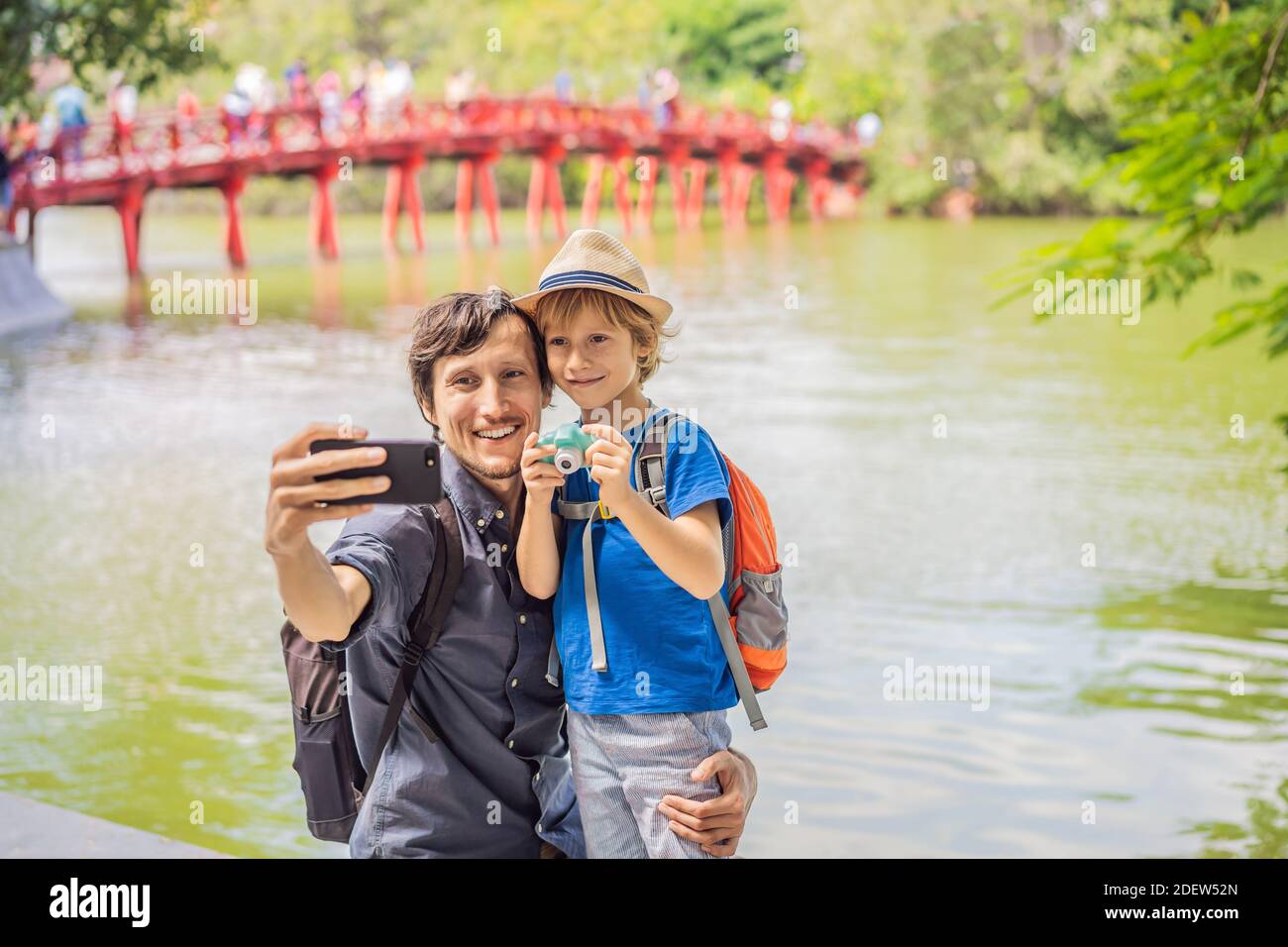 Caucasian Dad and son travelers on background of Red Bridge in public ...