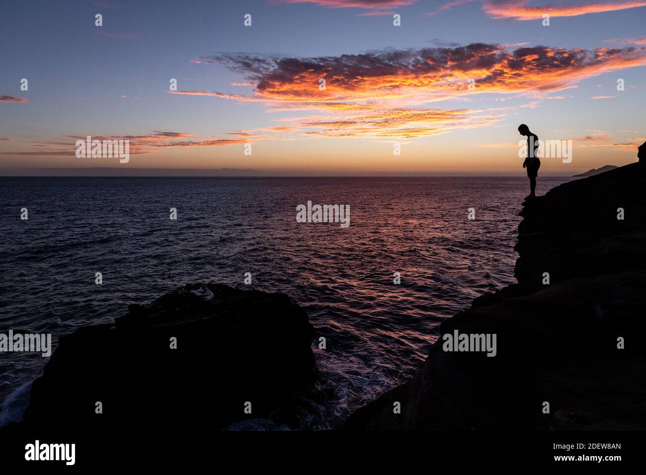 Cliff diver prepares to jump into the ocean at sunset in hawaii Stock ...