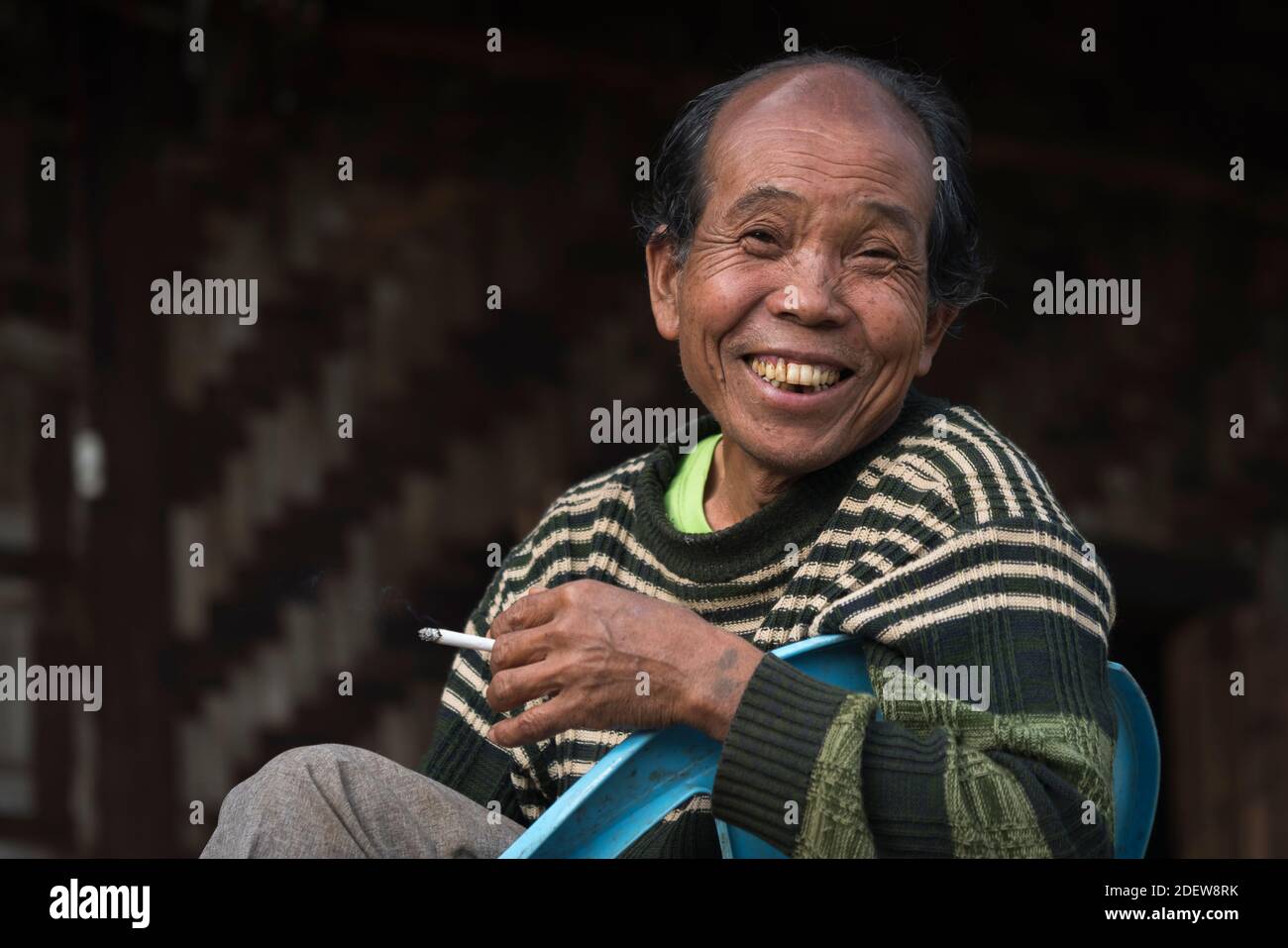Burmese man of Palong tribe smoking cigarette and smiling at camera ...