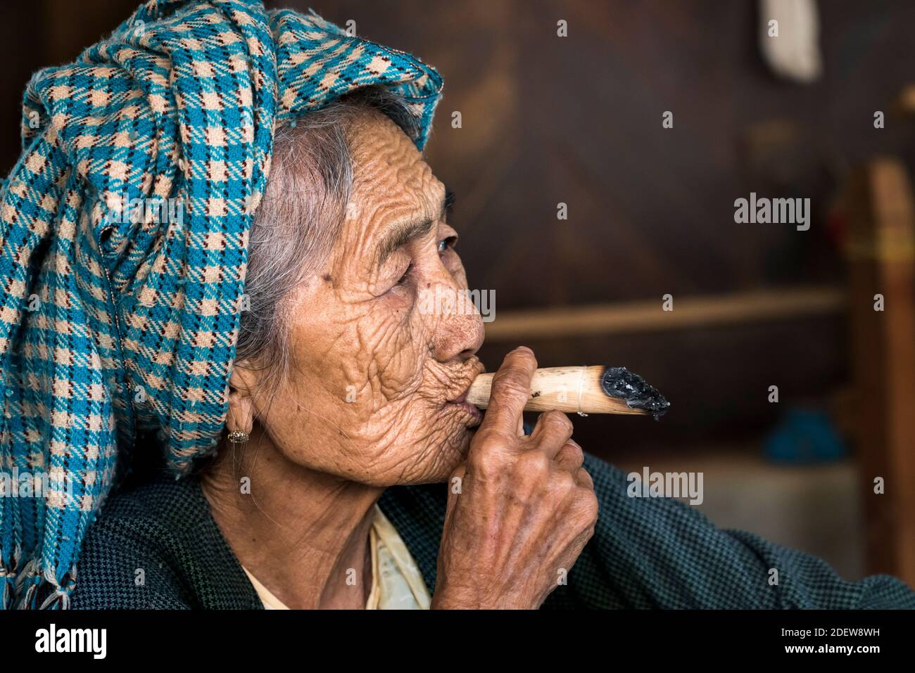 Side view of contemplated senior Burmese woman smoking cigar, Bagan ...