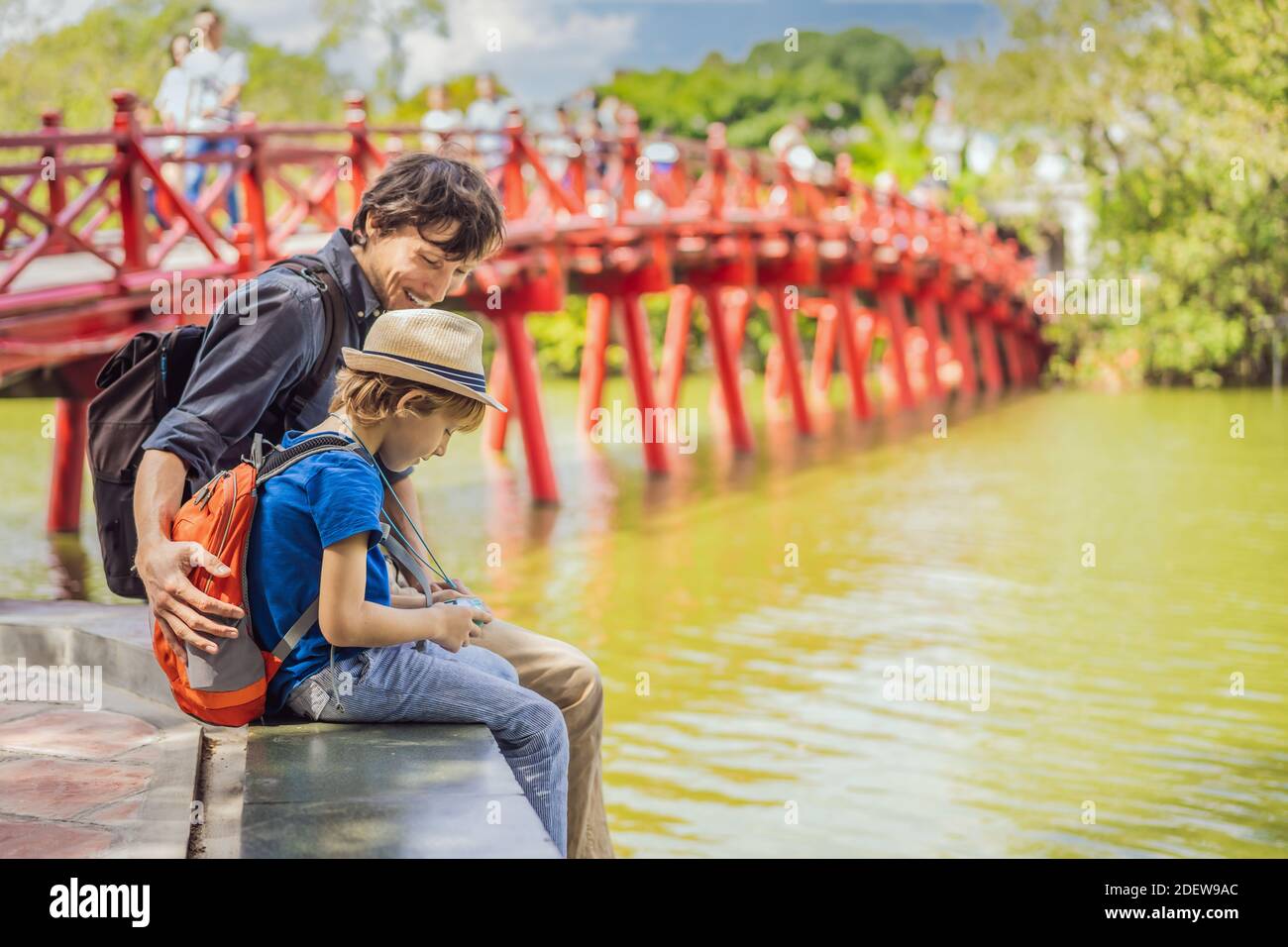 Caucasian Dad and son travelers on background of Red Bridge in public ...