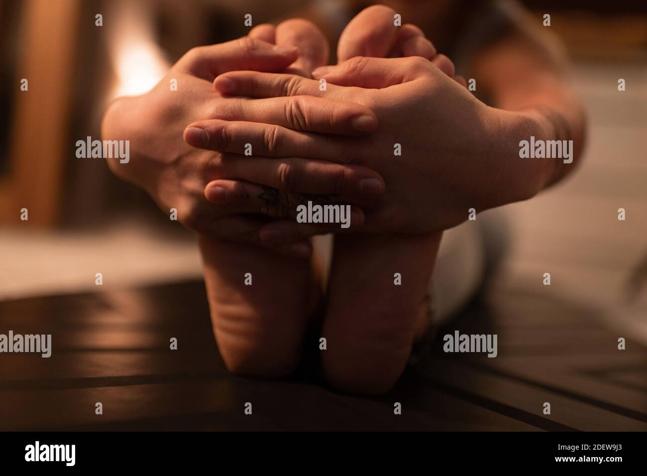 Cropped barefoot woman doing Seated Forward Bend pose during yoga ...