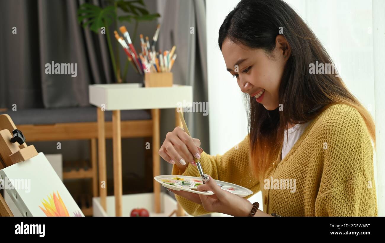A young painter smiling and working on painting in a workshop Stock ...
