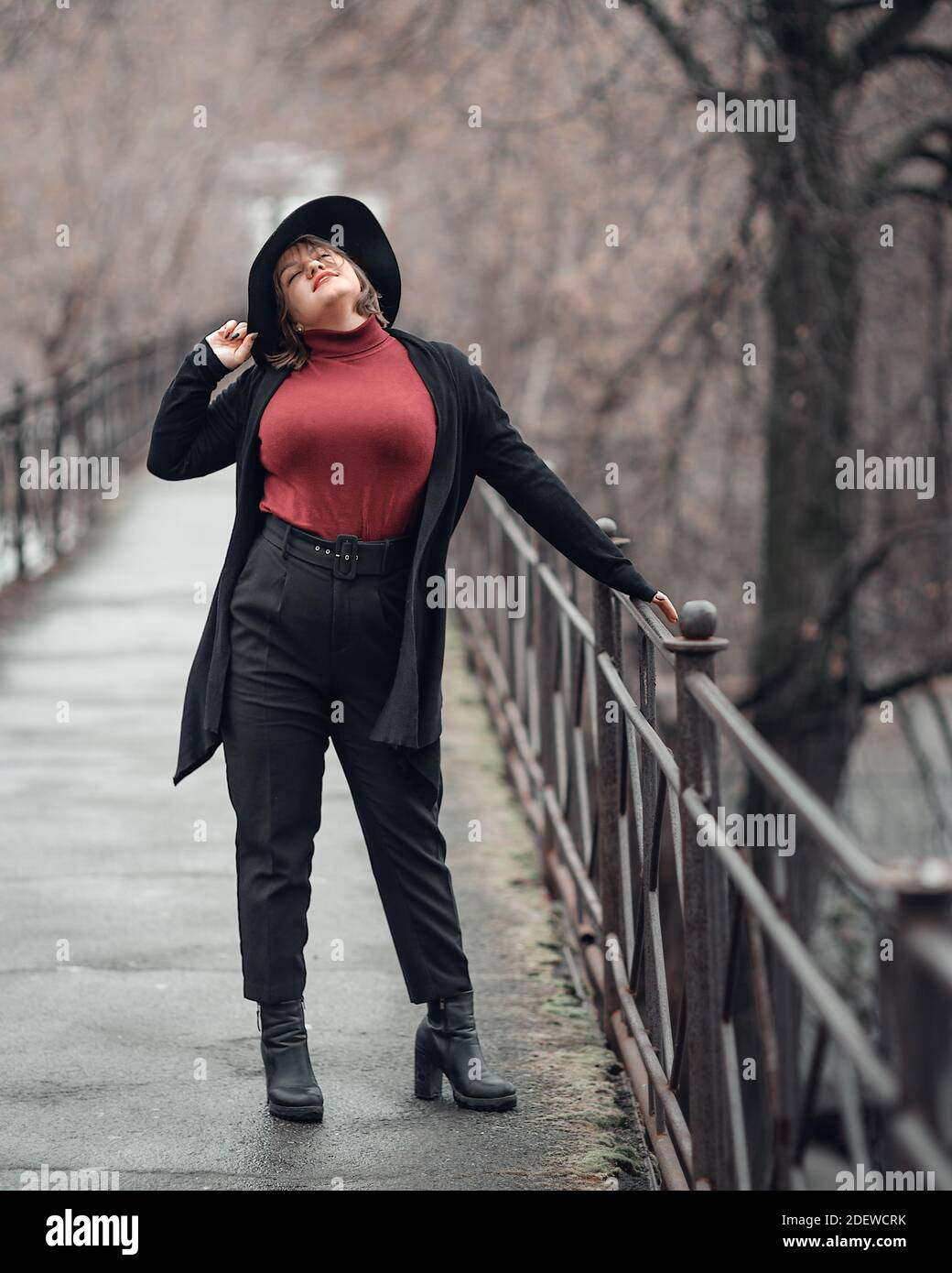 Brunette girl in hat on the bridge in cit in autumn. Plus size model ...