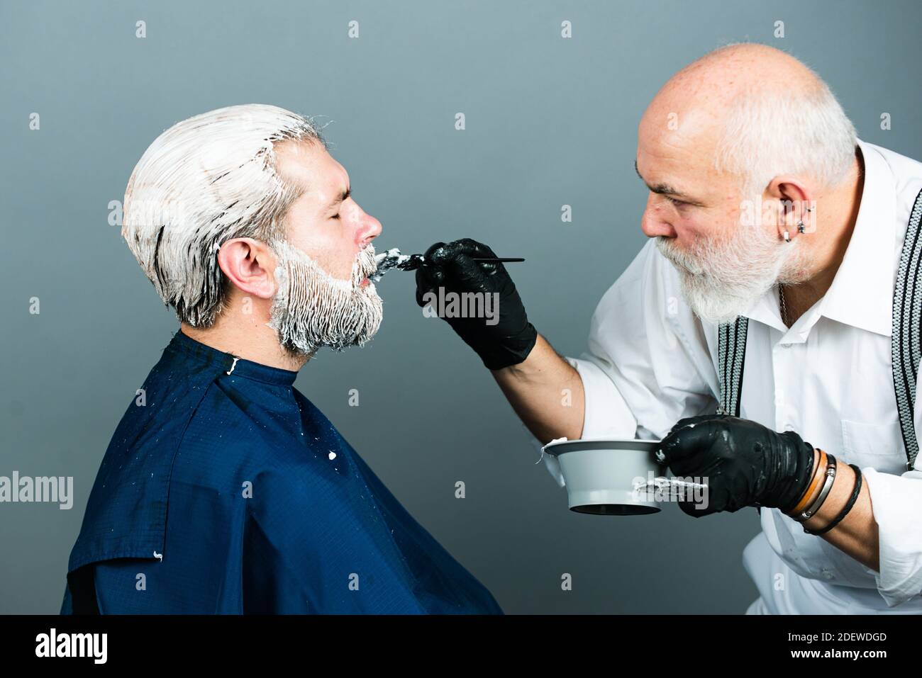 Stylist man with hair dye and brush coloring hair at salon. Process of ...