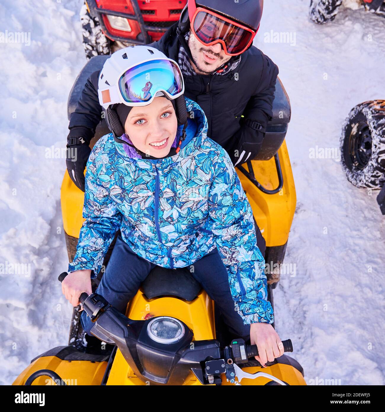Top view of joyful young woman and man in helmets and goggles driving ...