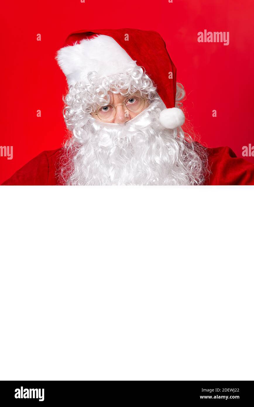 Santa Claus looking out from behind the blank white board isolated on ...