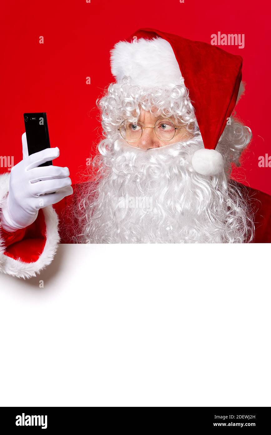 Santa Claus holding mobile phone in hand while standing behind the ...
