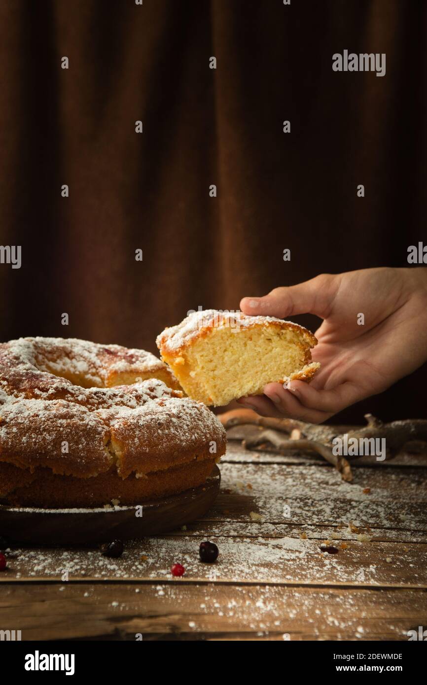 A vertical shot of a hand taking a piece of a delicious sponge cake ...