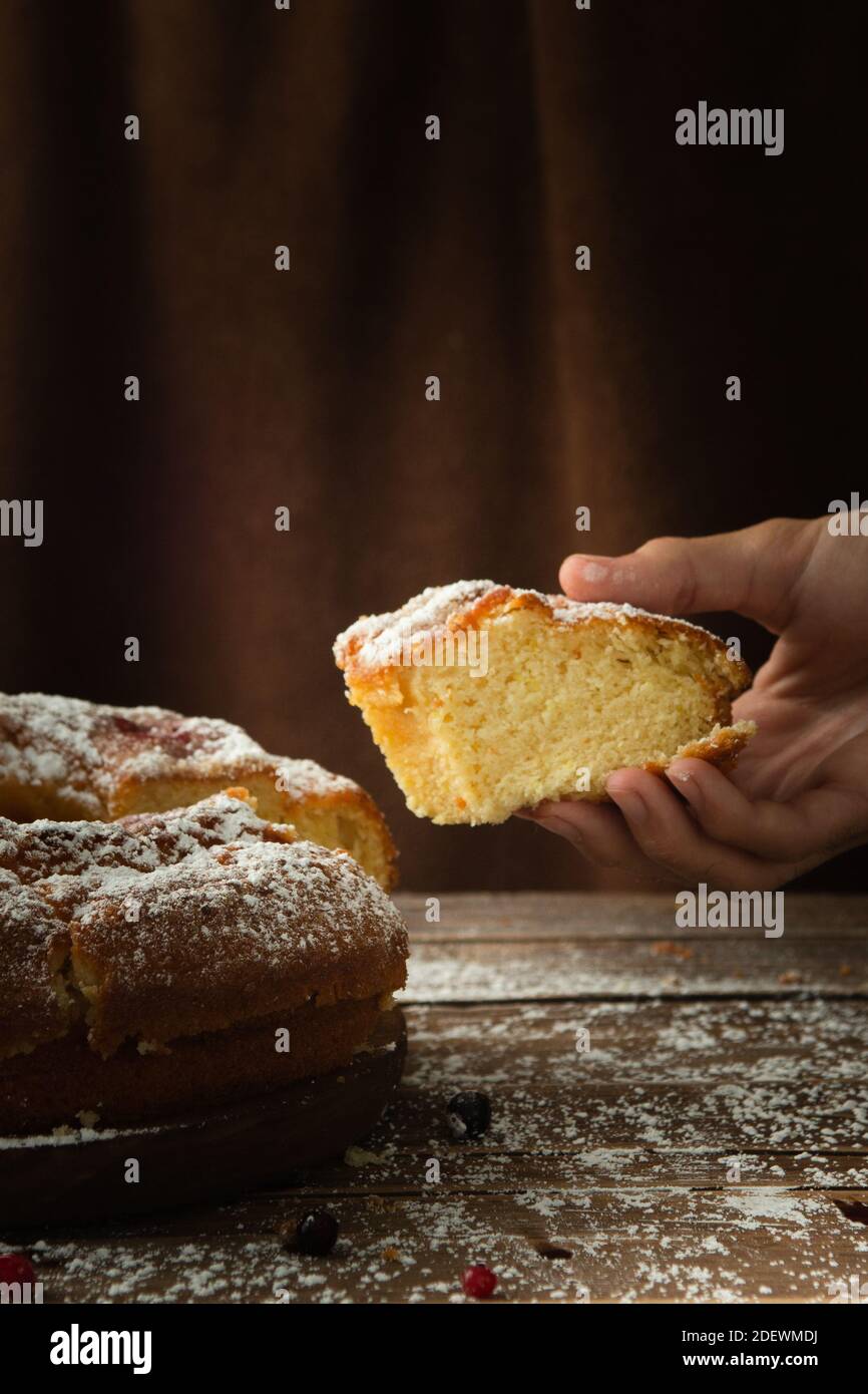 A vertical shot of a hand taking a piece of a delicious sponge cake ...