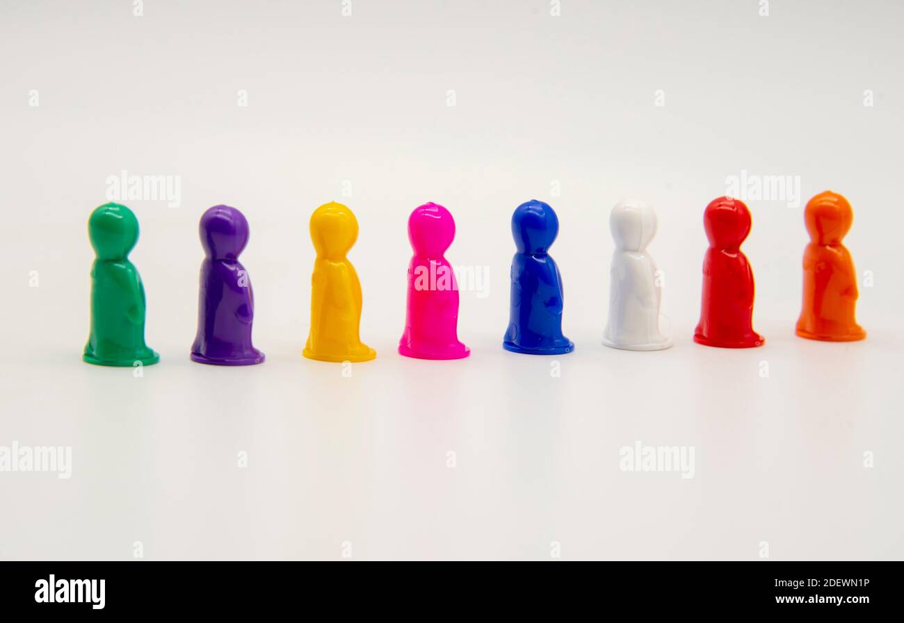 Miniature plastic toy figures stand in formation on a white background ...