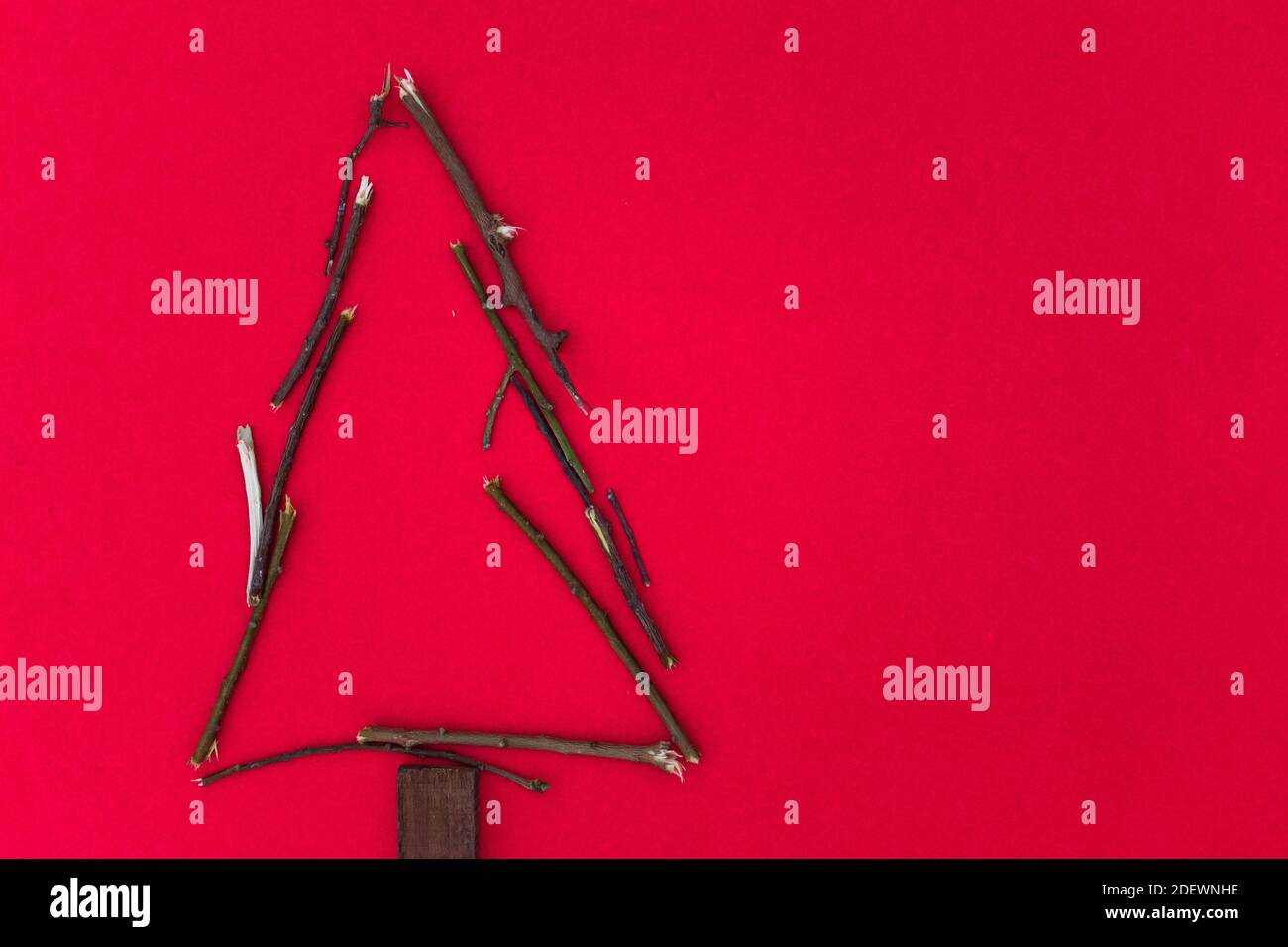A conceptual Christmas tree made from scrap wood on a red background ...