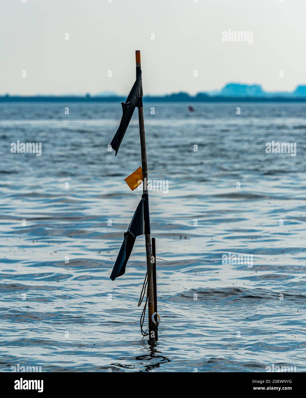 Pole with flags marking the location of underwater fishing nets along ...