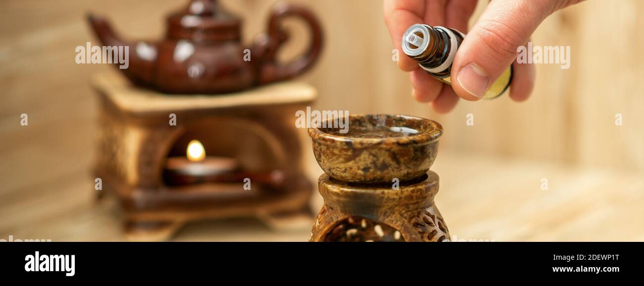 Hand of therapist pours drops of essential oil to a ceramic diffuser in ...
