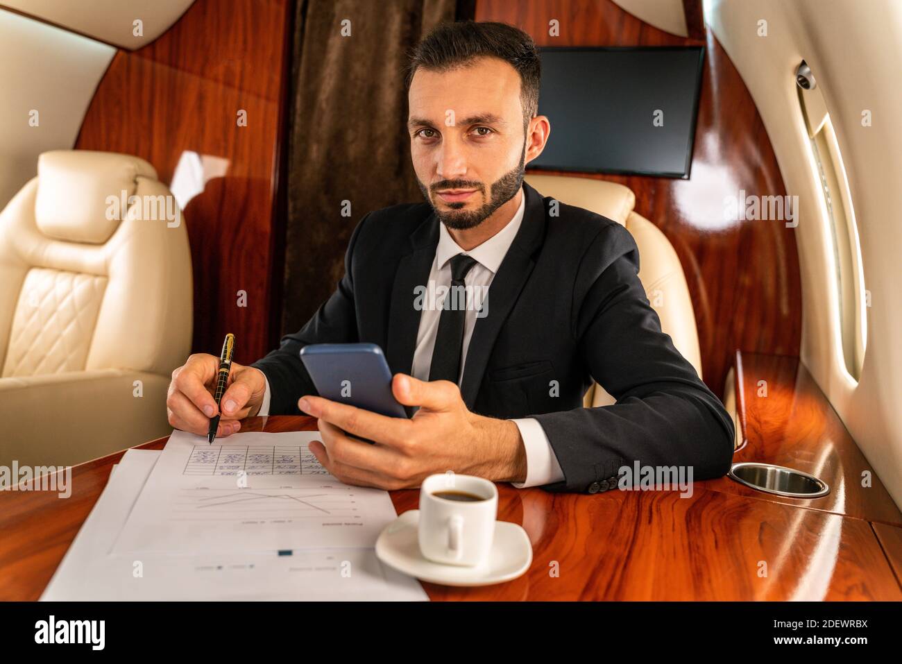 Handsome businessman wearing elegant suit flying on exclusive private ...