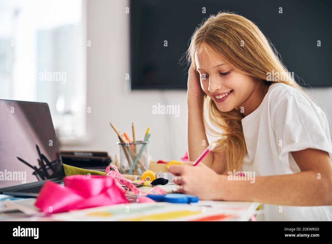 Pleased young fashion designer writing down her ideas Stock Photo - Alamy