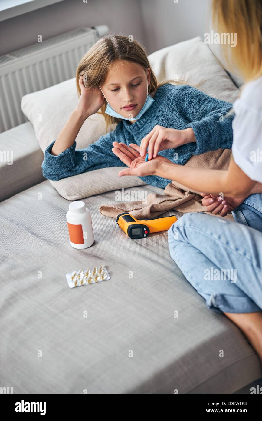 Diseased kid taking the tablets from her mother hand Stock Photo - Alamy
