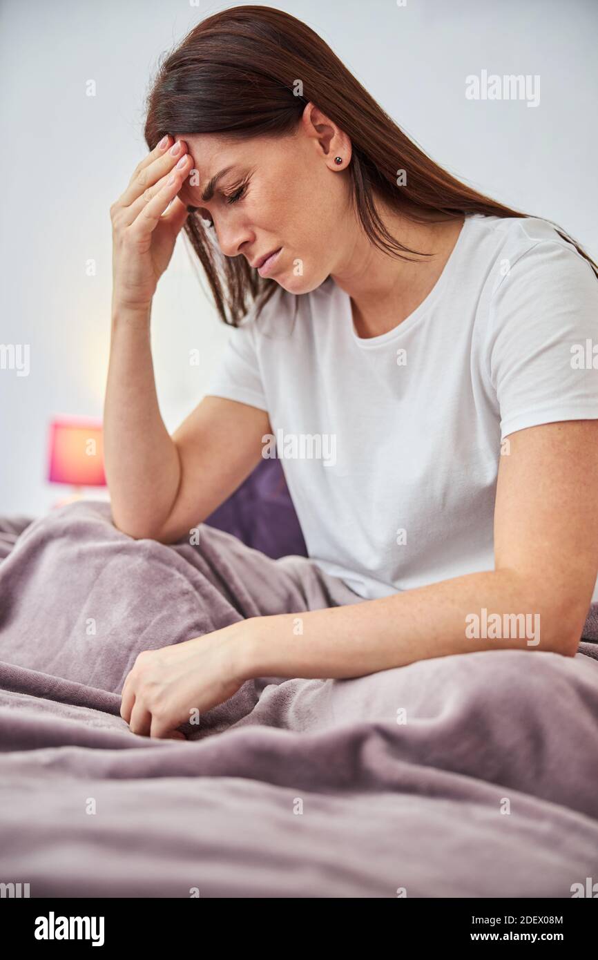 Suffering female placing a hand on her forehead Stock Photo - Alamy