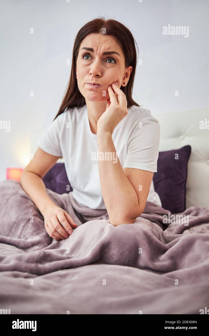 Sick housewife palping her jaw with fingers Stock Photo - Alamy
