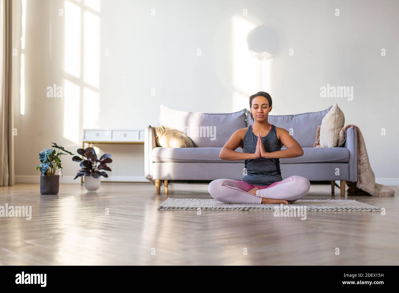 Yoga practice at home. African American woman meditating while doing ...
