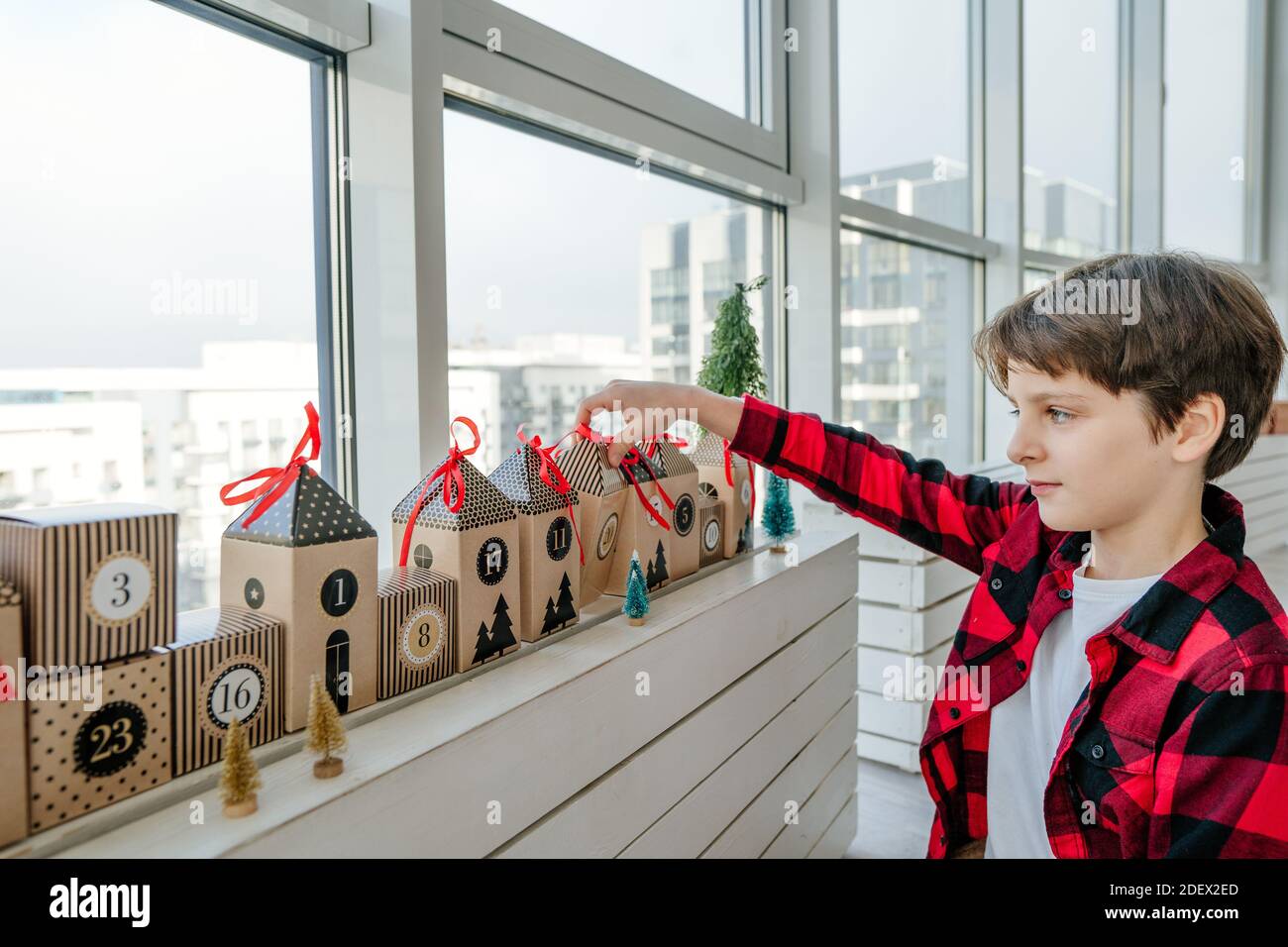 Boy opening Christmas handmade advent calendar in a house shape to ...