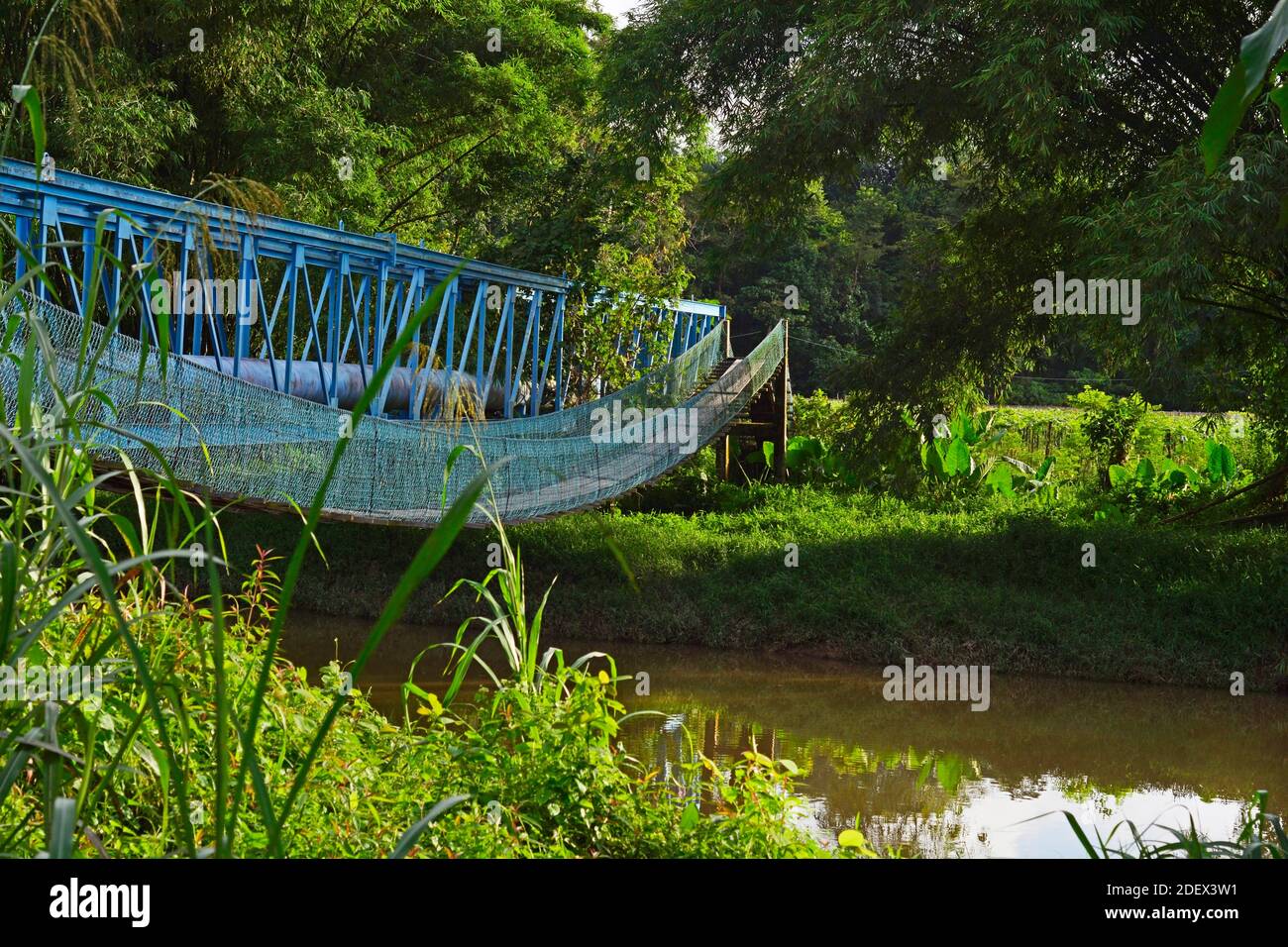 Water steel pipe and hanging bridge over river in rural area in ...