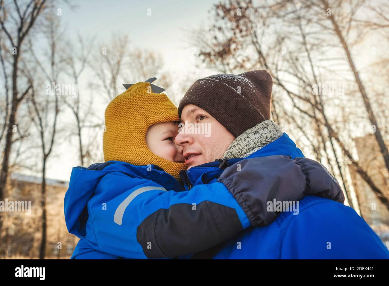 Father have a fun with his little son in a park. Winter, cold. Blue ...