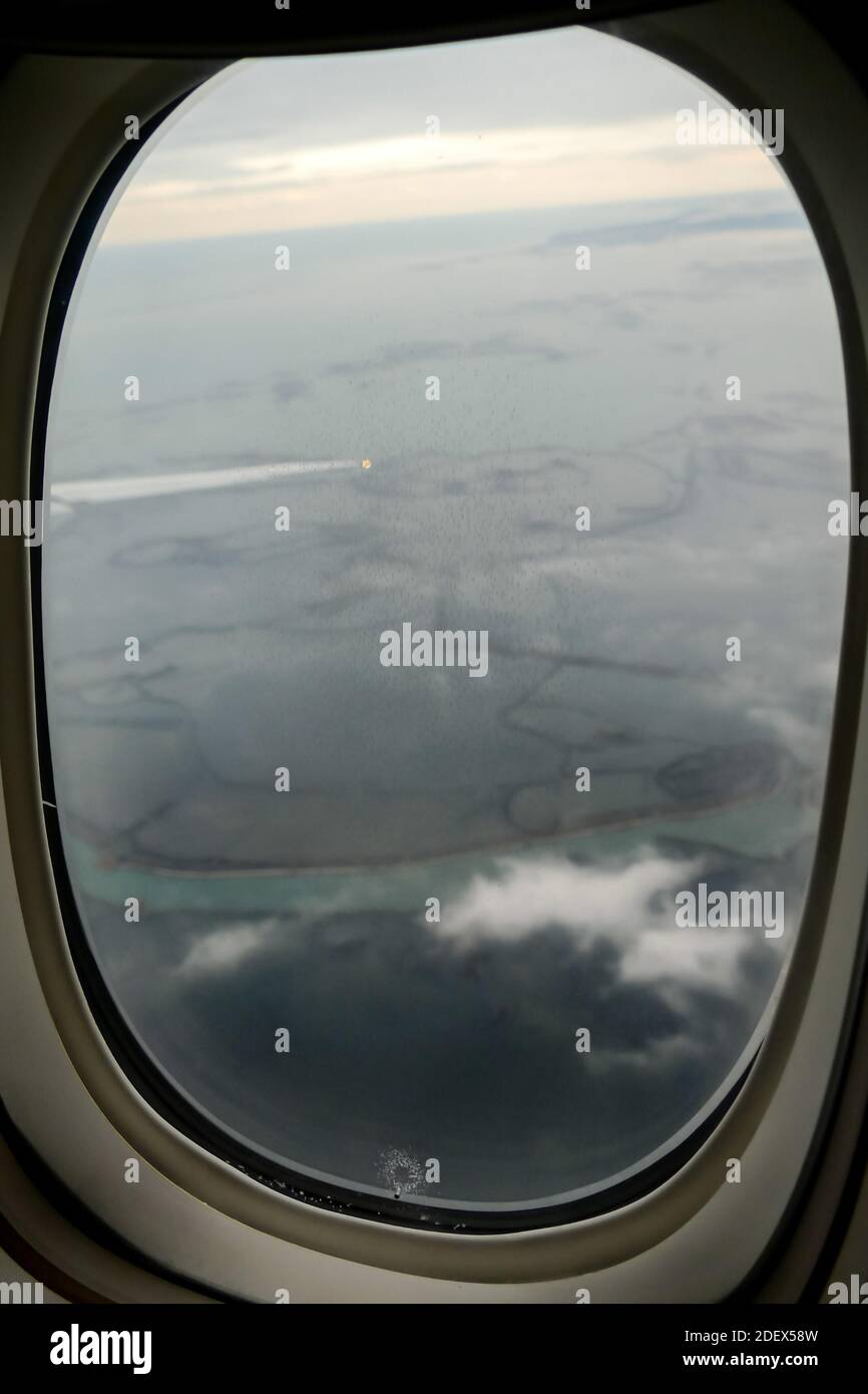 A vertical shot of an airplane window with a beautiful landscape view ...