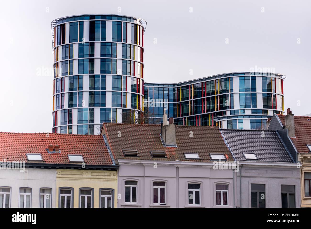 A modern curved building with glass walls behind a block of old ...