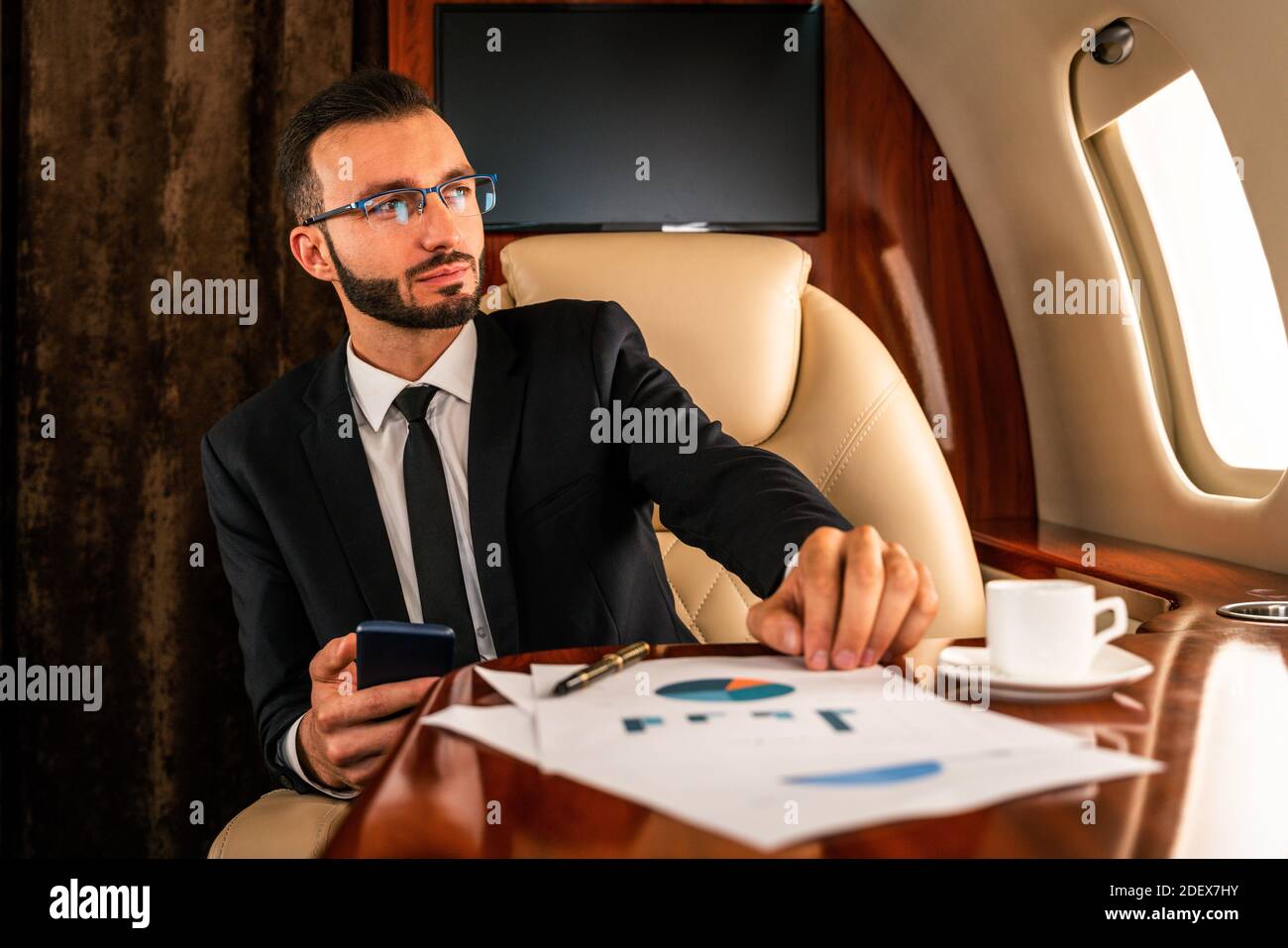 Handsome businessman wearing elegant suit flying on exclusive private ...