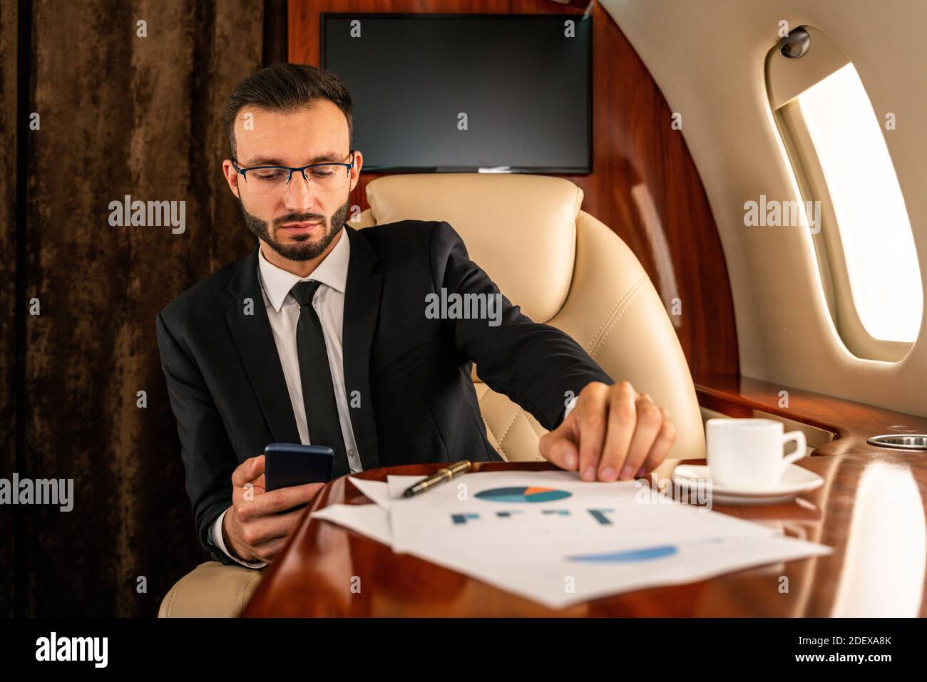 Handsome businessman wearing elegant suit flying on exclusive private ...