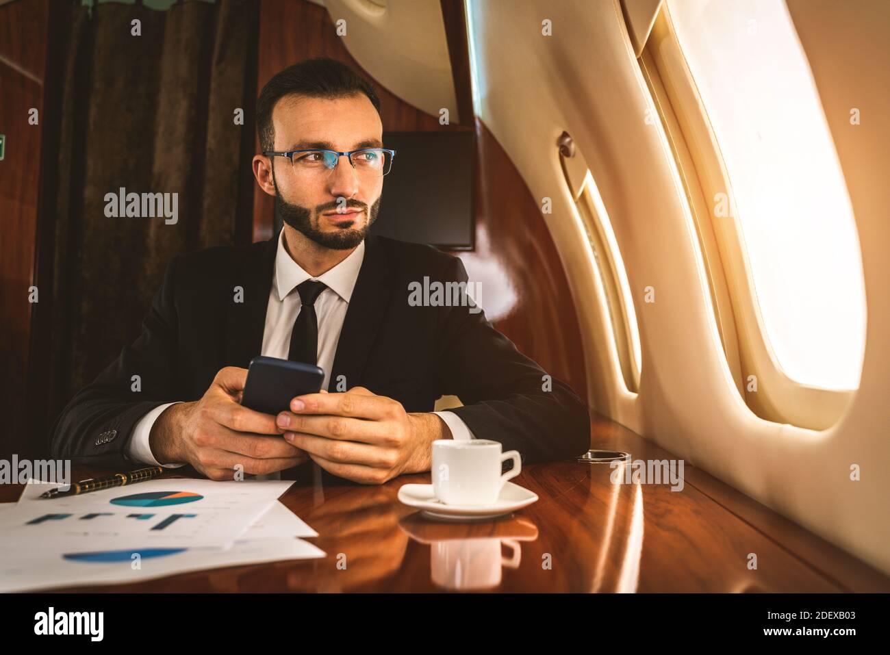 Handsome businessman wearing elegant suit flying on exclusive private ...