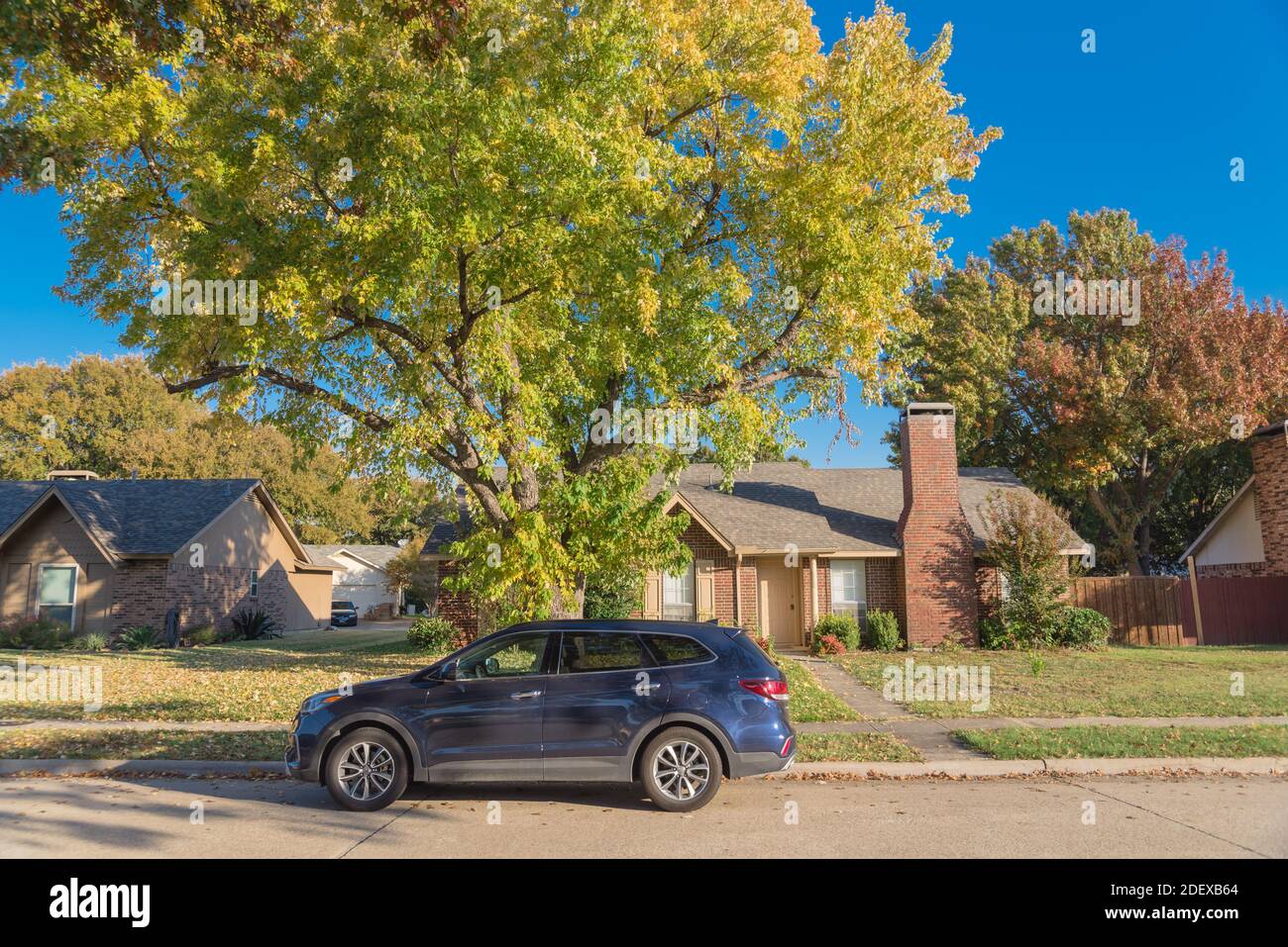 Typical residential street with parked car in front of residential ...