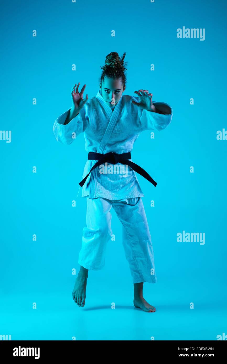 Attack. Professional female judoist in white judo kimono practicing and ...