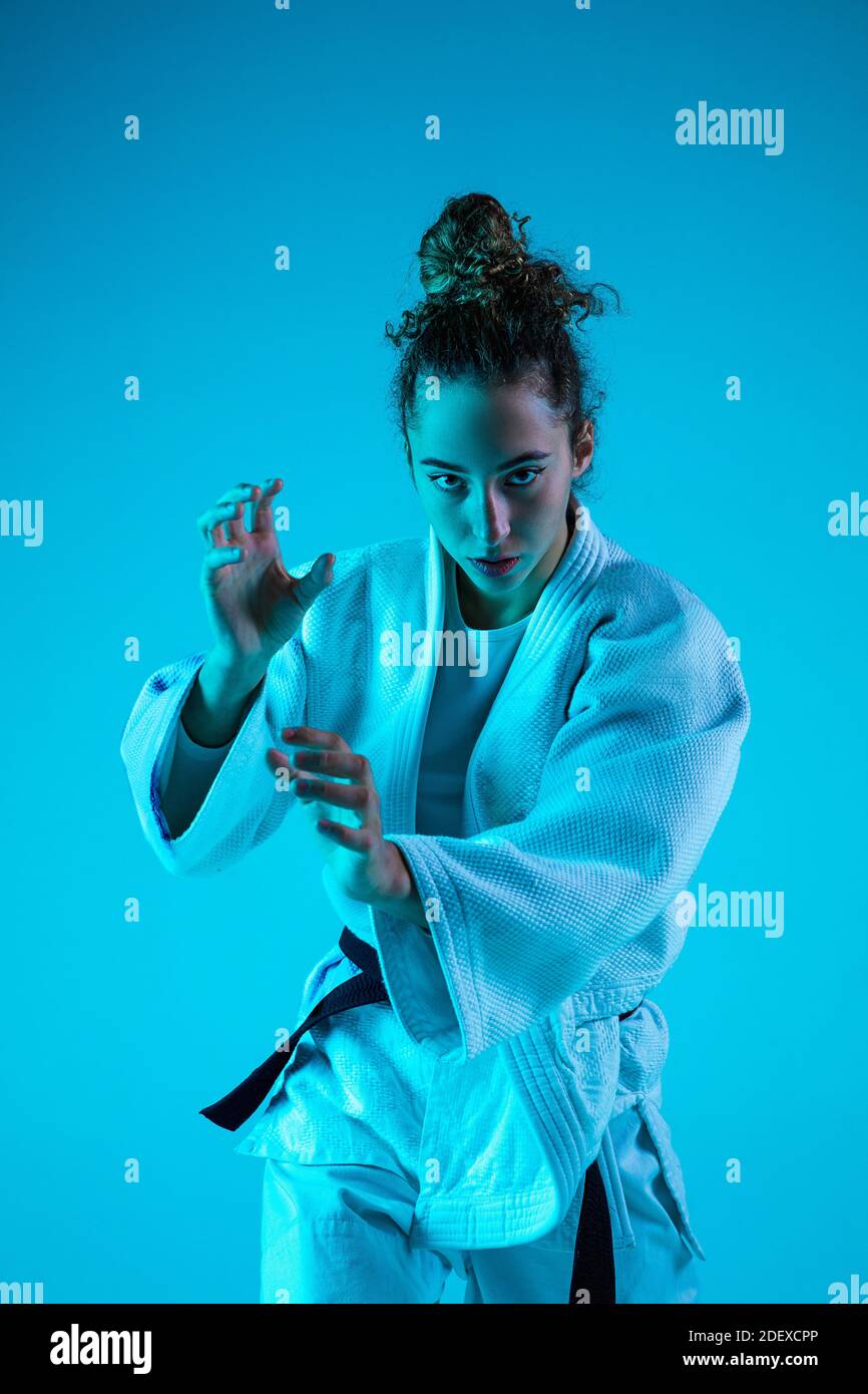 Attack. Professional female judoist in white judo kimono practicing and training isolated on ...