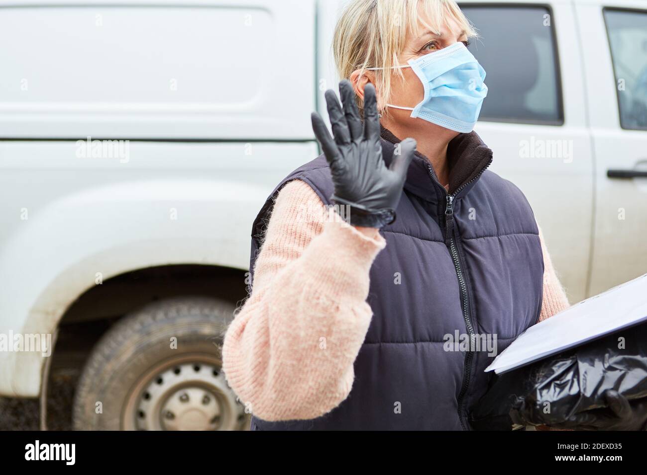 Delivery service parcel handler with face mask gives hand signals ...