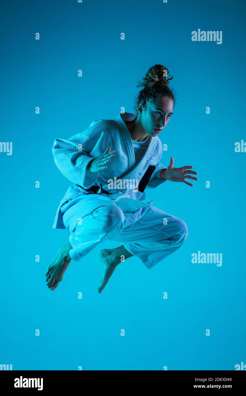 Jumping. Professional female judoist in white judo kimono practicing ...