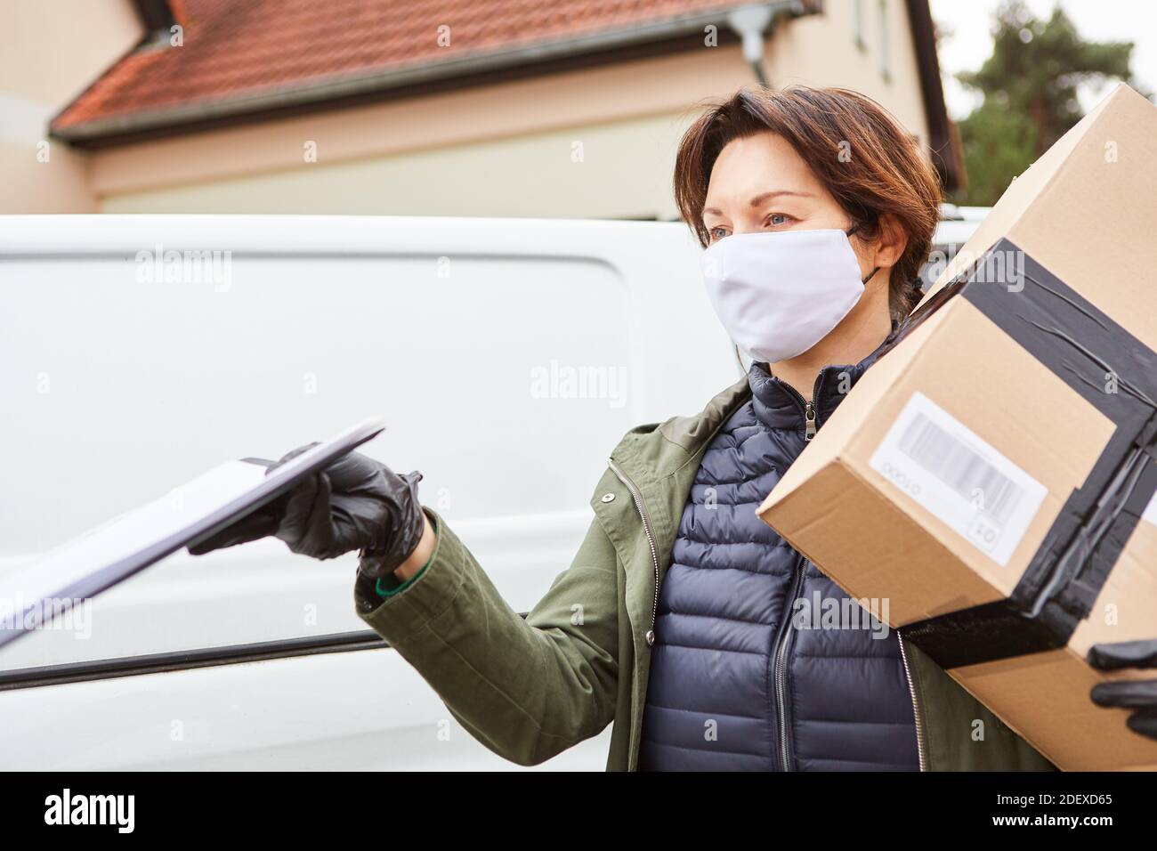 Delivery service parcel handler with face mask holds list for parcel ...