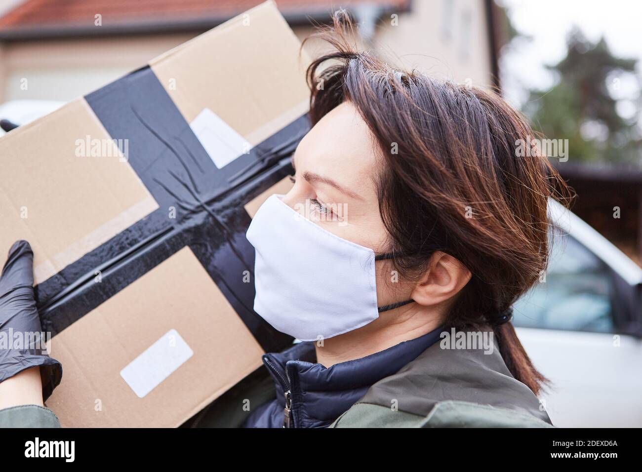 Delivery service parcel handler with face mask carries the parcel for ...