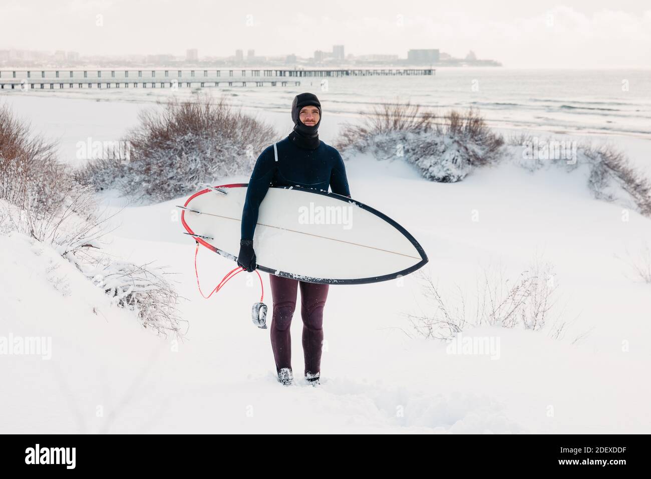Snowy cold winter and man surfer with surfboard. Winter coastline and ...