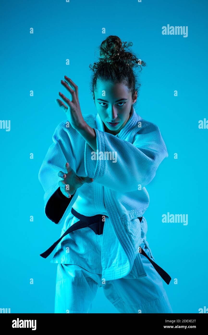 Attack. Professional female judoist in white judo kimono practicing and ...