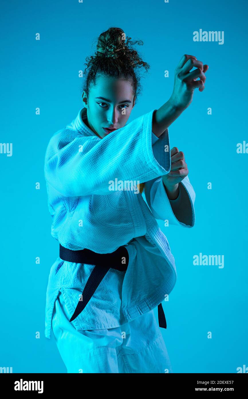 Attack. Professional female judoist in white judo kimono practicing and training isolated on ...