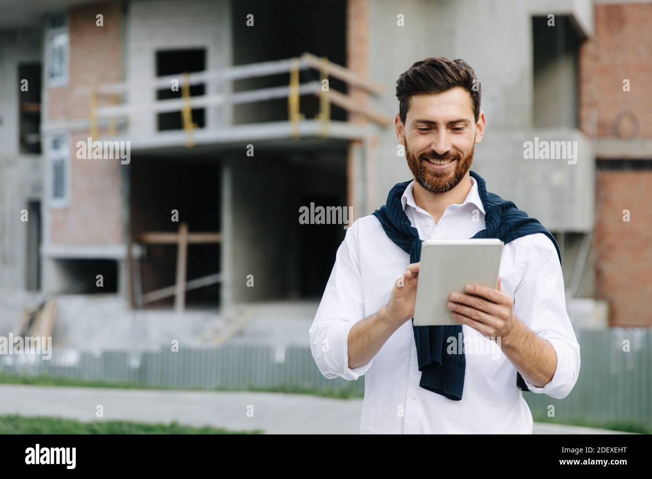 Smiling engineer looking at tablet screen outdoors Stock Photo - Alamy