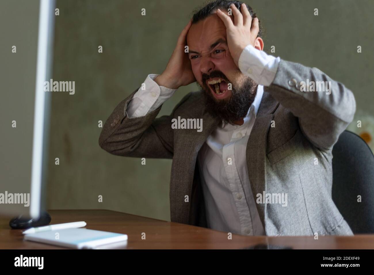young bearded businessman yelling holding his head with his hands ...